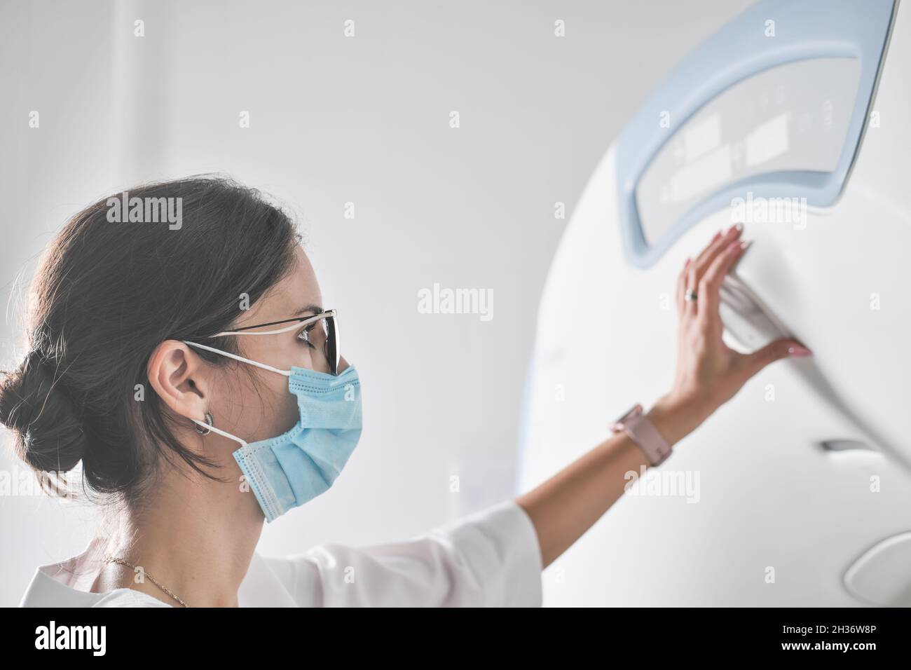 woman radiologist doctor adjusting computer tomography scanner machine ...