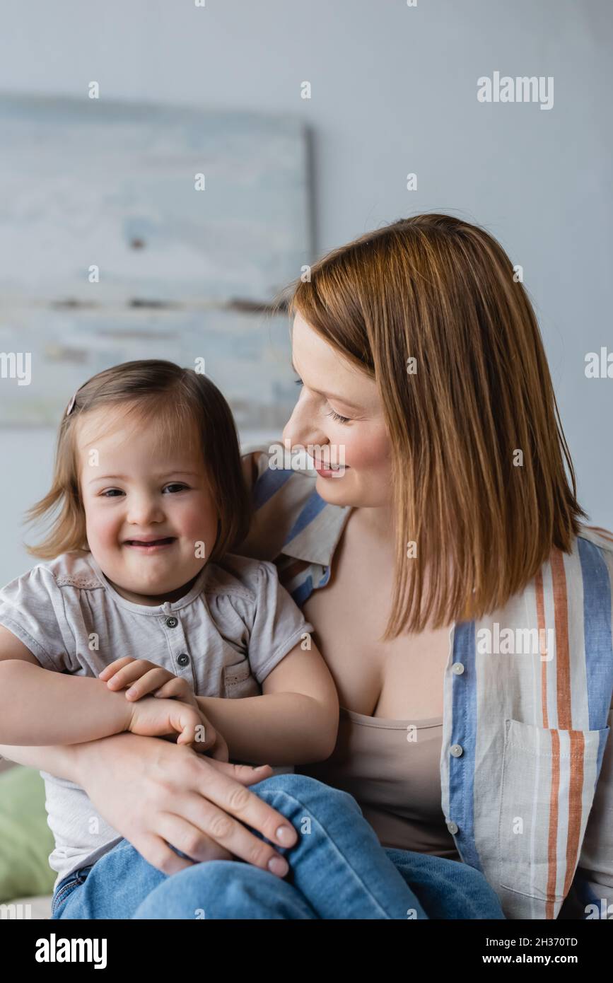 Smiling mother hugging daughter with down syndrome in bedroom Stock ...