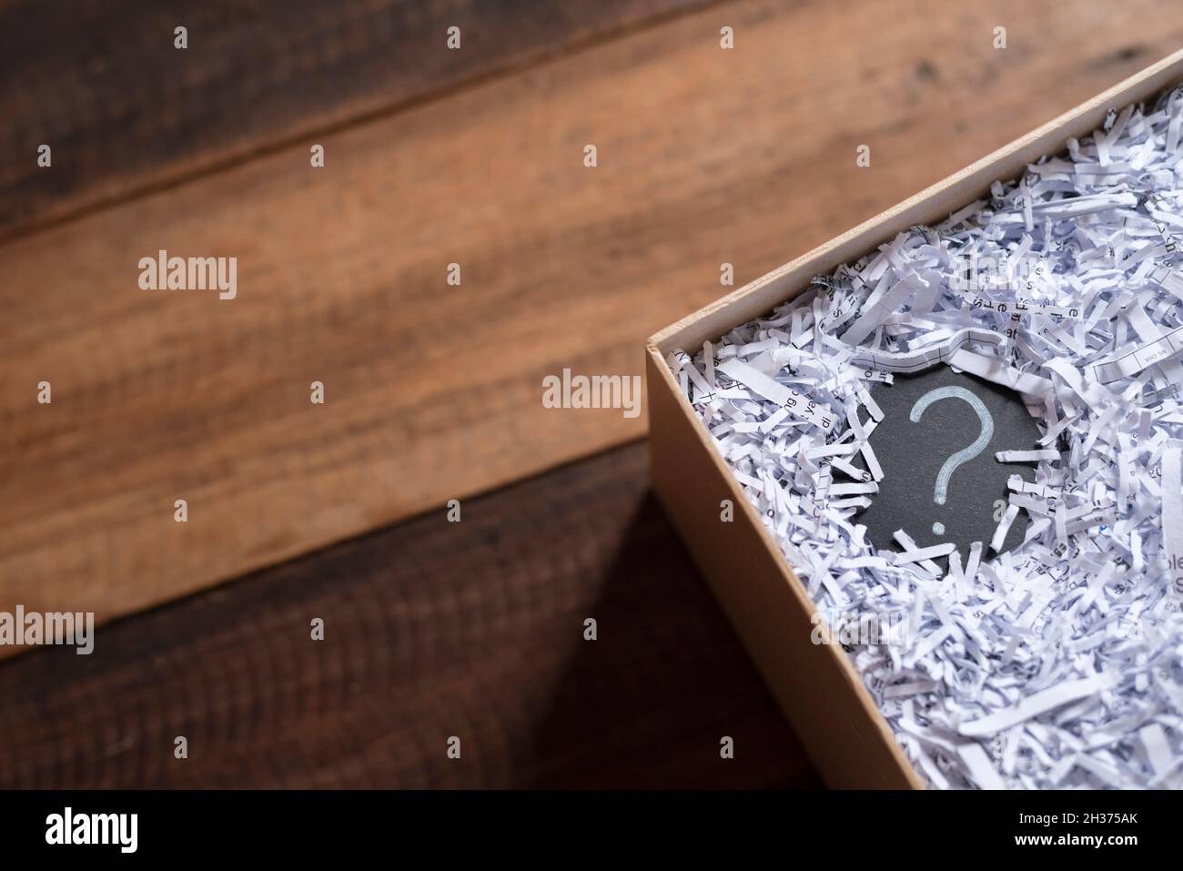 Question mark in a box with shredded paper on wooden table. Concept of ...
