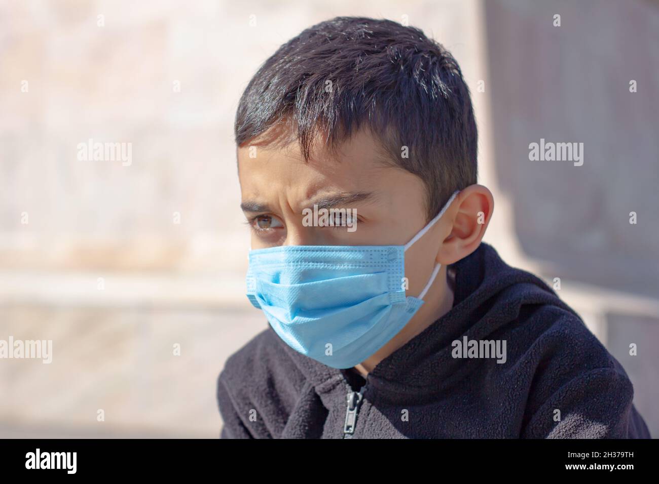Bored, frustrated kid concept wearing face mask. Brunette boy in black ...