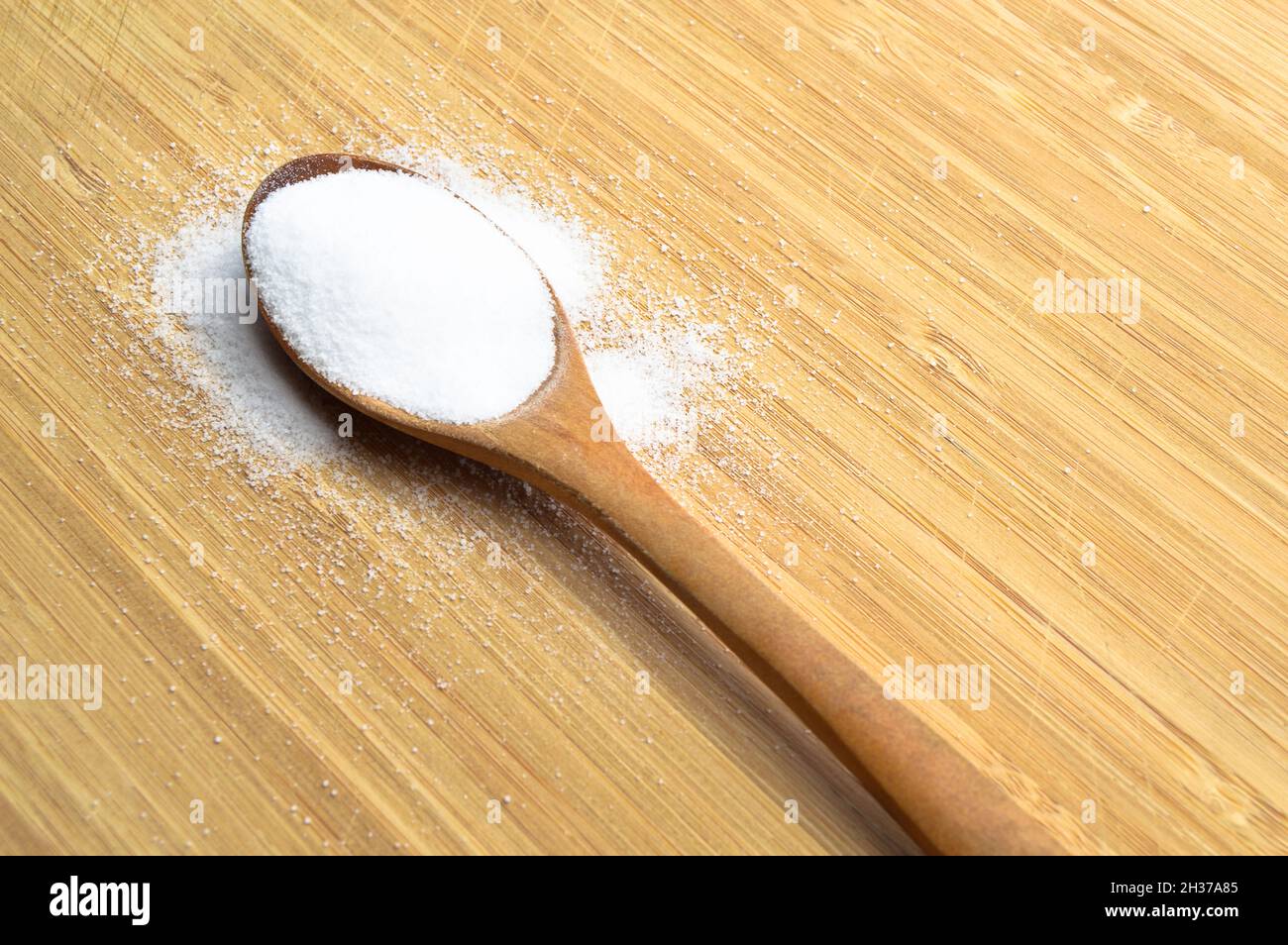 Table salt used in cooking in wooden spoon on bamboo cutting board ...