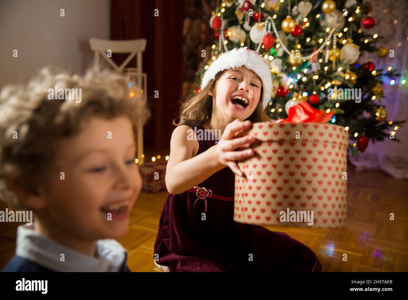 Excited cute kids happily smiling, opening Christmas gifts. Beautifully ...