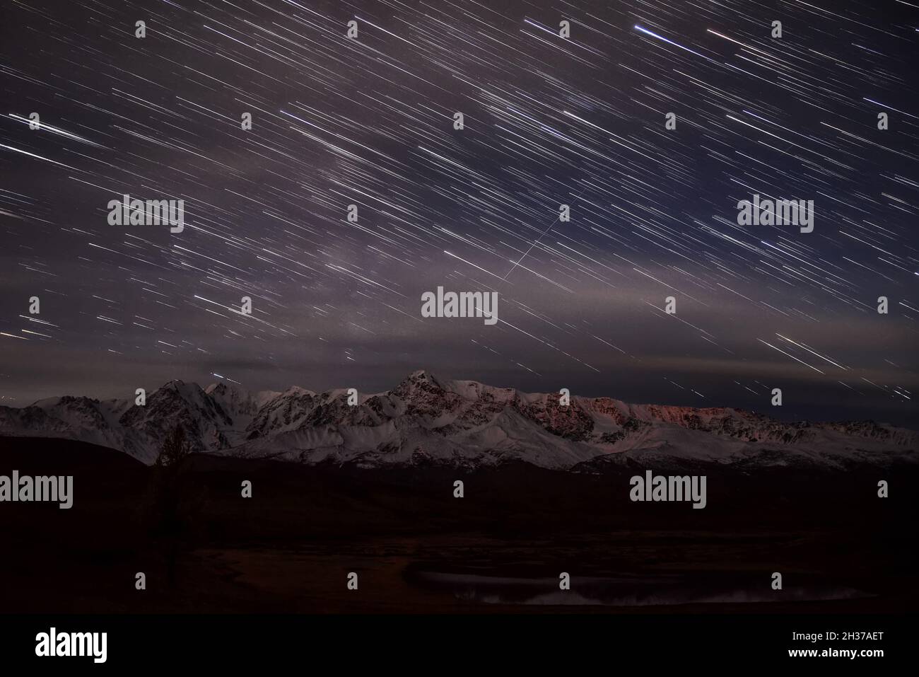 Amazing night view with stars in the form of tracks and blurry clouds ...