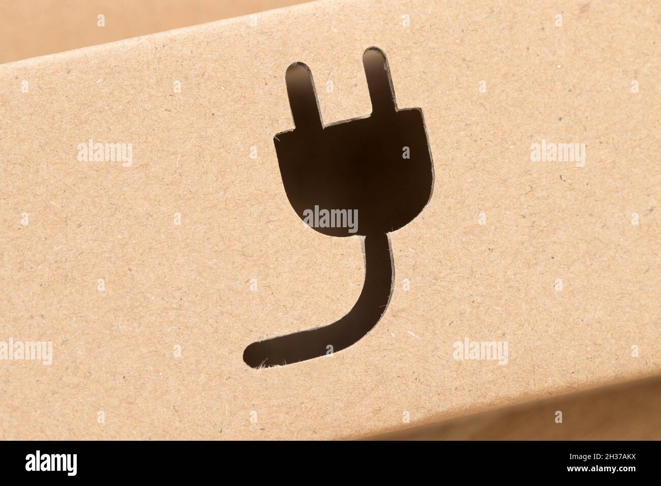 Electrical plug symbol cut out on cardboard packaging Stock Photo - Alamy
