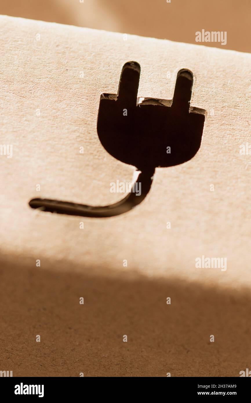 Electrical plug symbol cut out on cardboard packaging Stock Photo - Alamy