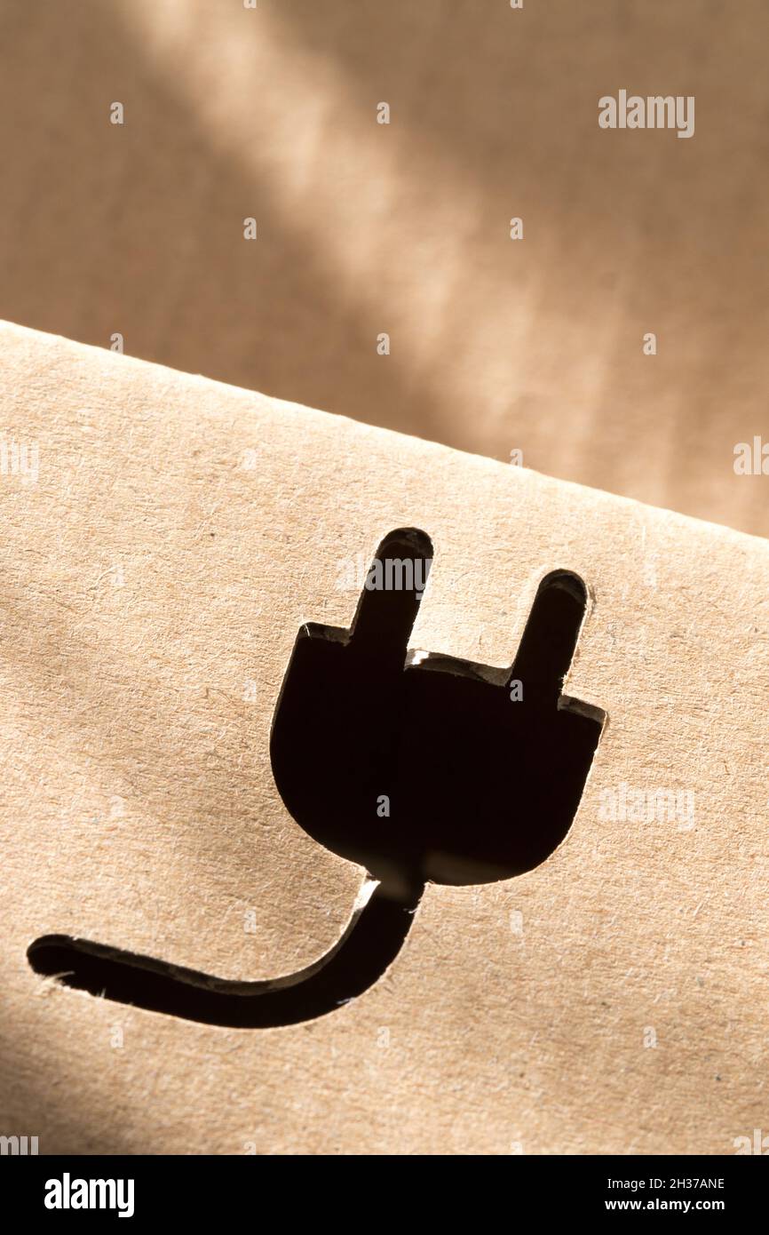 Electrical plug symbol cut out on cardboard packaging Stock Photo - Alamy