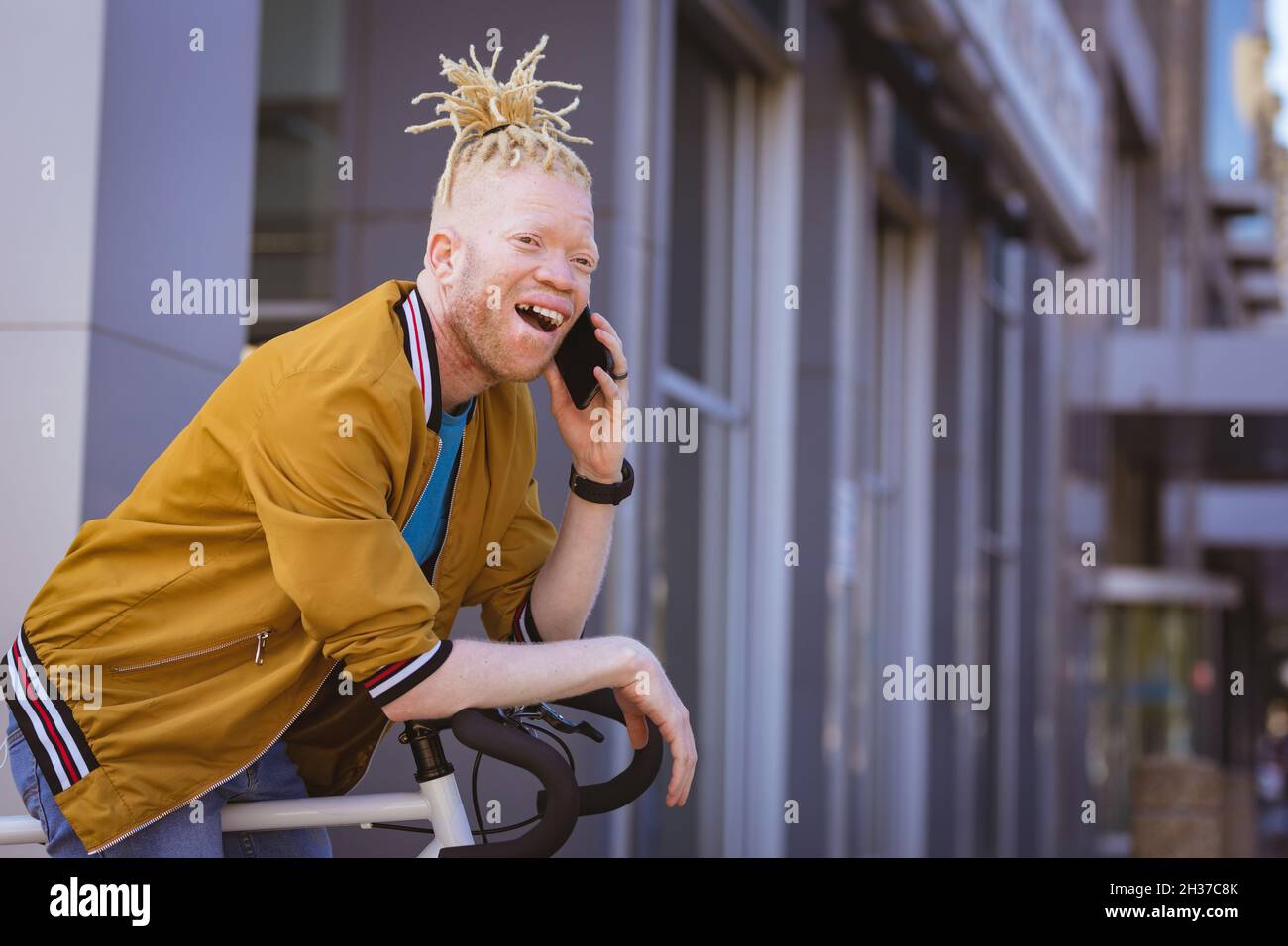 Happy albino african american man with dreadlocks talking on smartphone ...