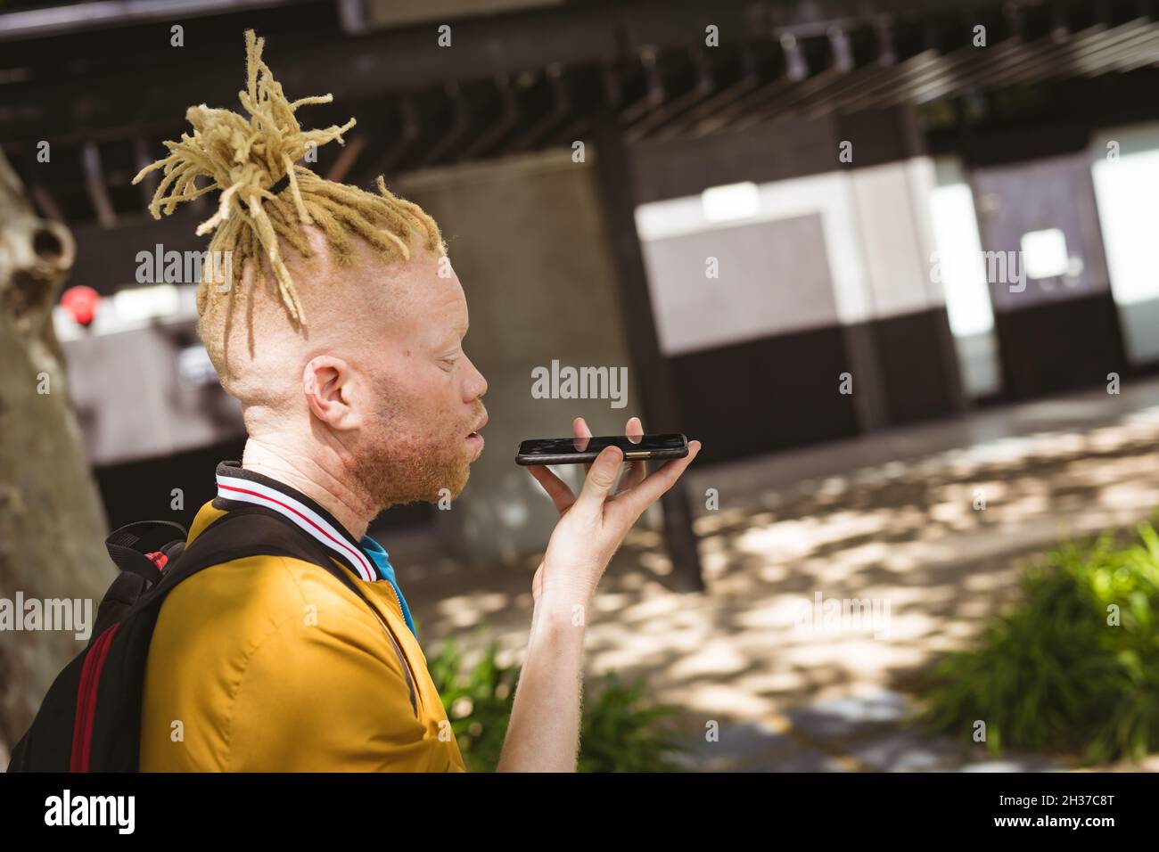 Happy albino african american man with dreadlocks on street talking on ...