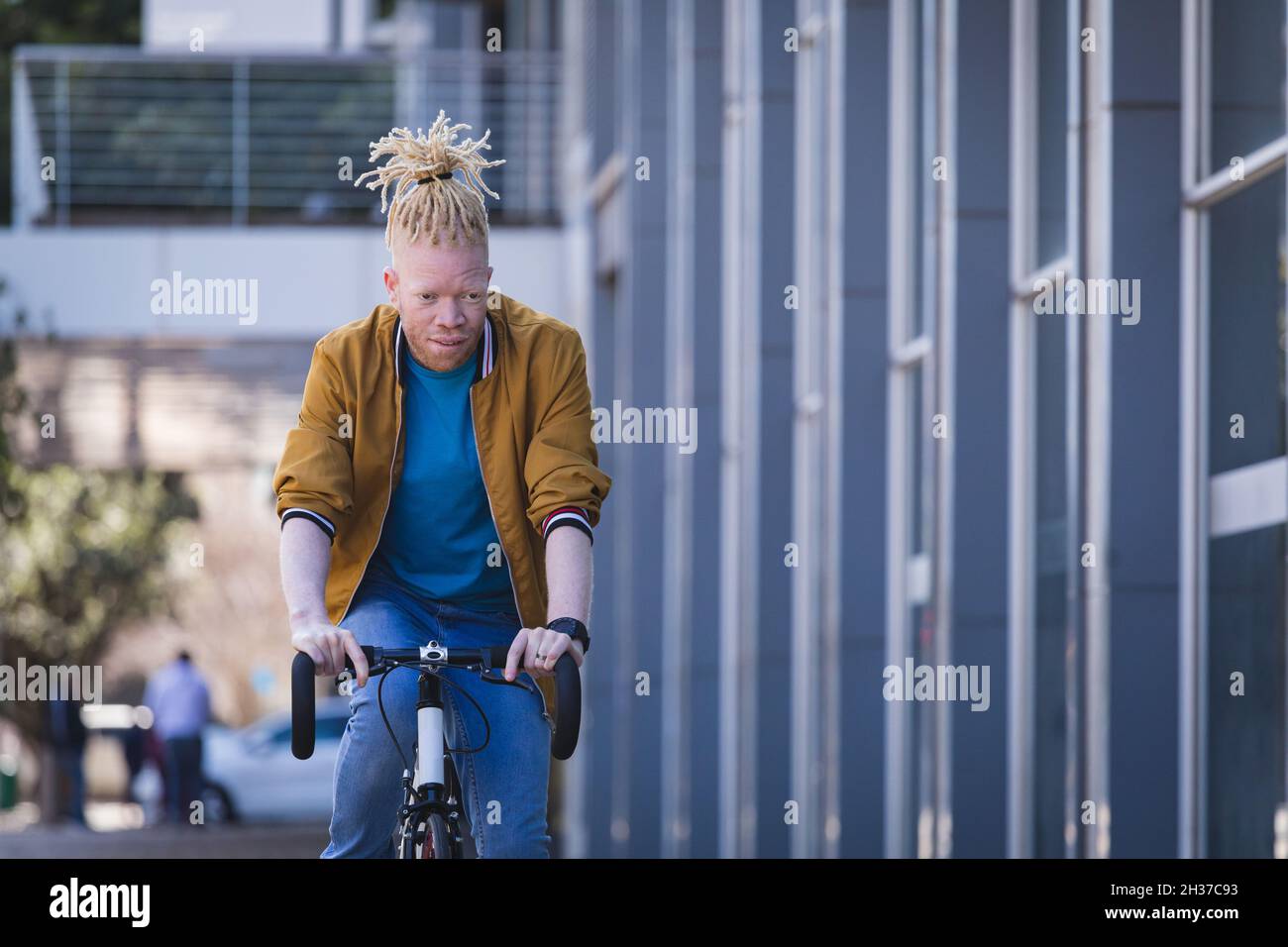 Thoughtful albino african american man with dreadlocks riding bike ...
