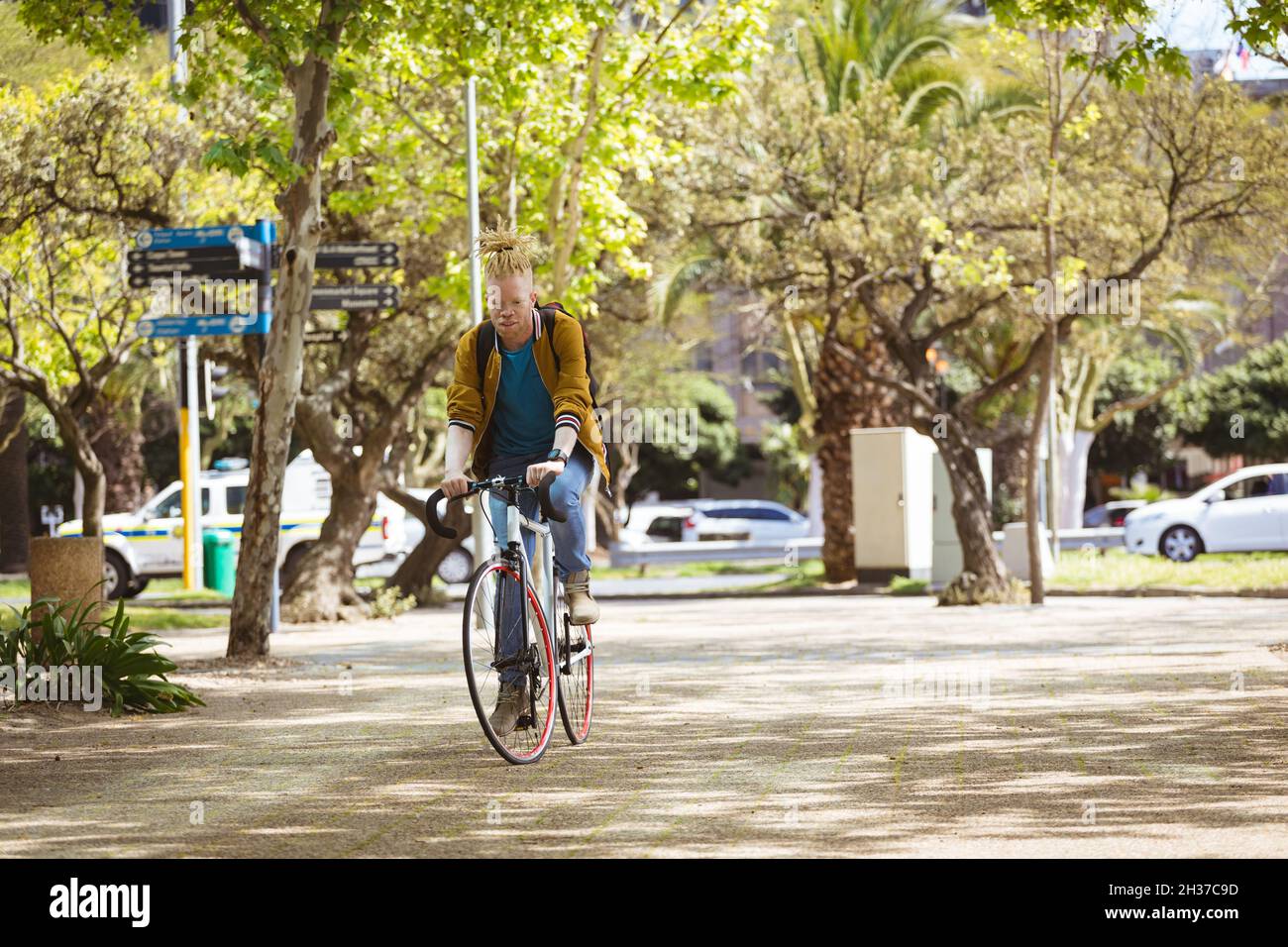 Thoughtful albino african american man with dreadlocks riding bike ...