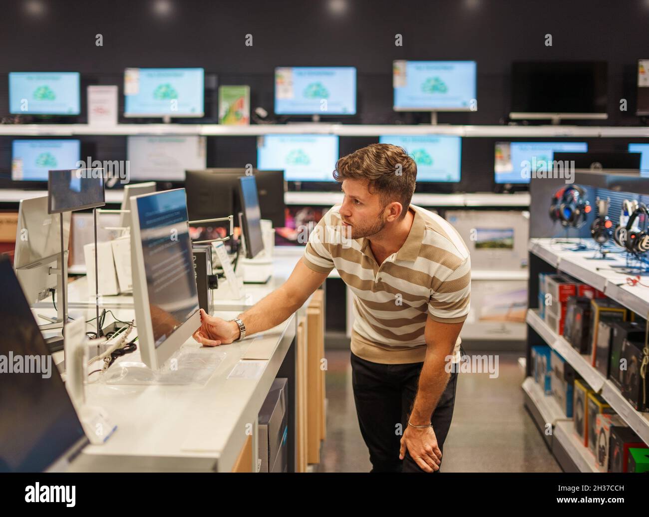 Male client in casual clothes examining new computer monitor on shelf ...