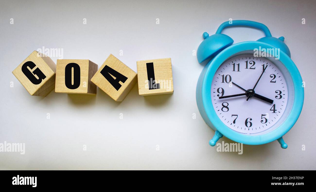 Word goal made with wooden blocks of letters next to blue alarm clock ...