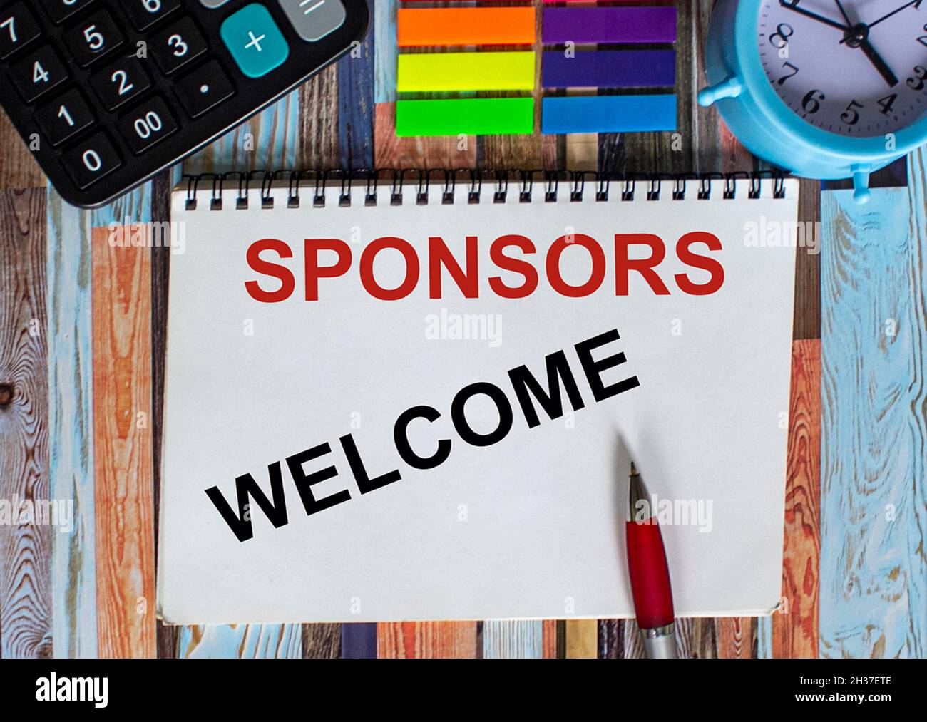WELCOME SPONSORS word written on notepad with alarm clock, calculator ...