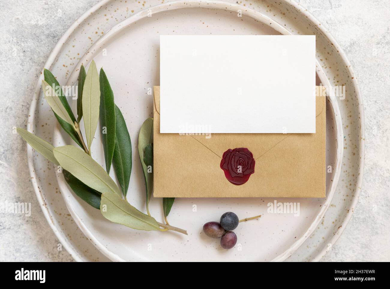Wedding invitation card and envelope over porcelain plates on white ...