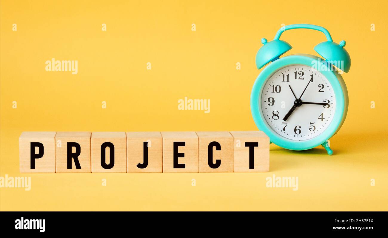Project word written in wooden cube and yellow background with clock ...