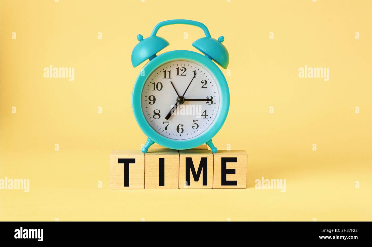 On a light yellow background, wooden cubes with the word TIME and with ...