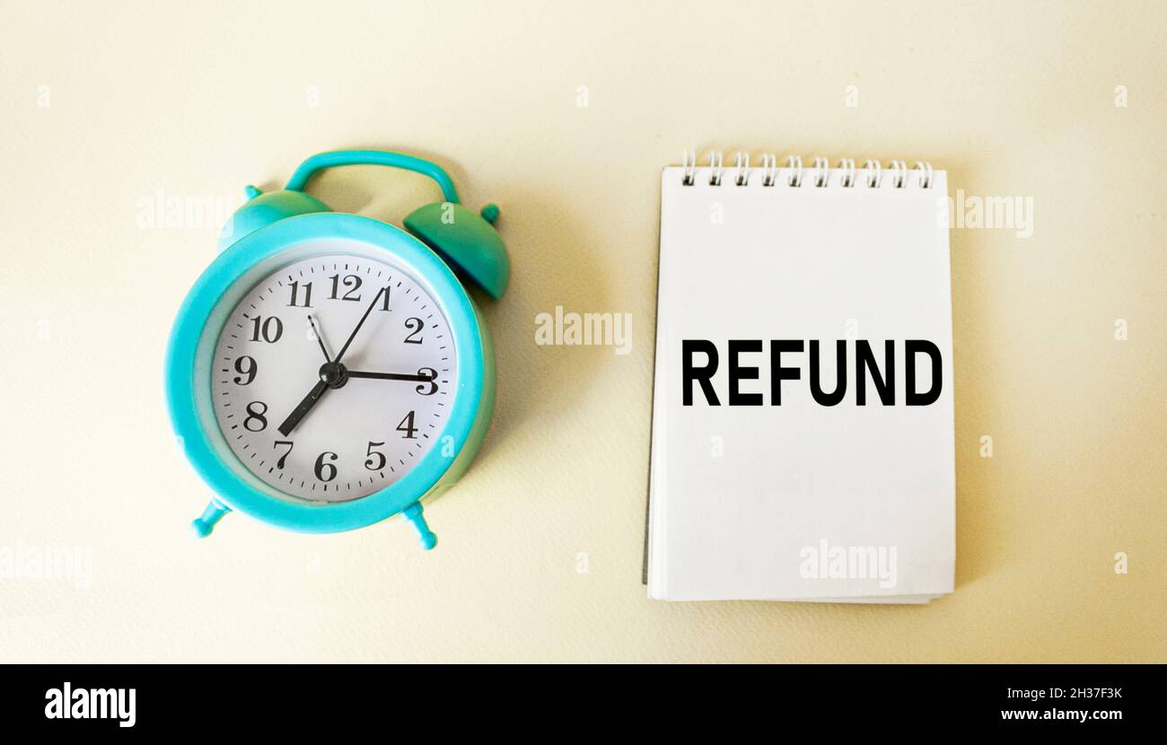 The word REFUND on a notepad and a light background, near an alarm ...