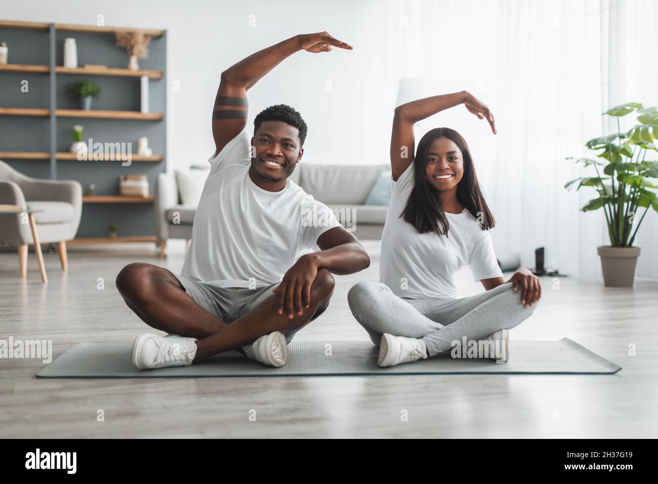 Young black couple doing side bend exercise together Stock Photo - Alamy