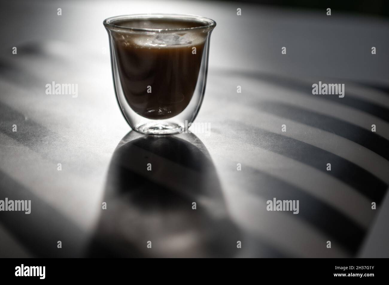 Close Up photo of cup with black coffee and shadow on black and white ...