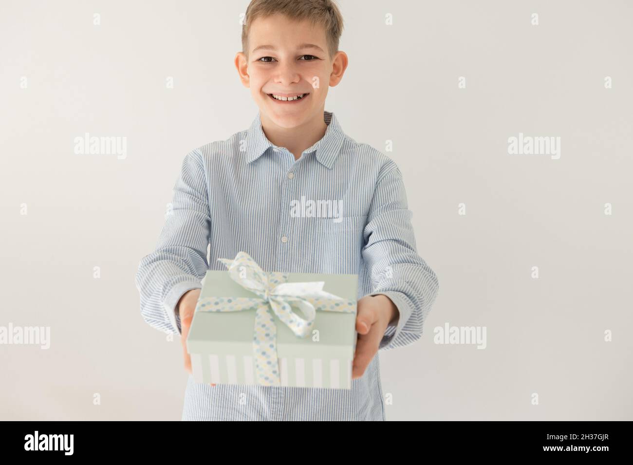 Cute smiling teenage boy giving beautiful gift box as birthday or ...