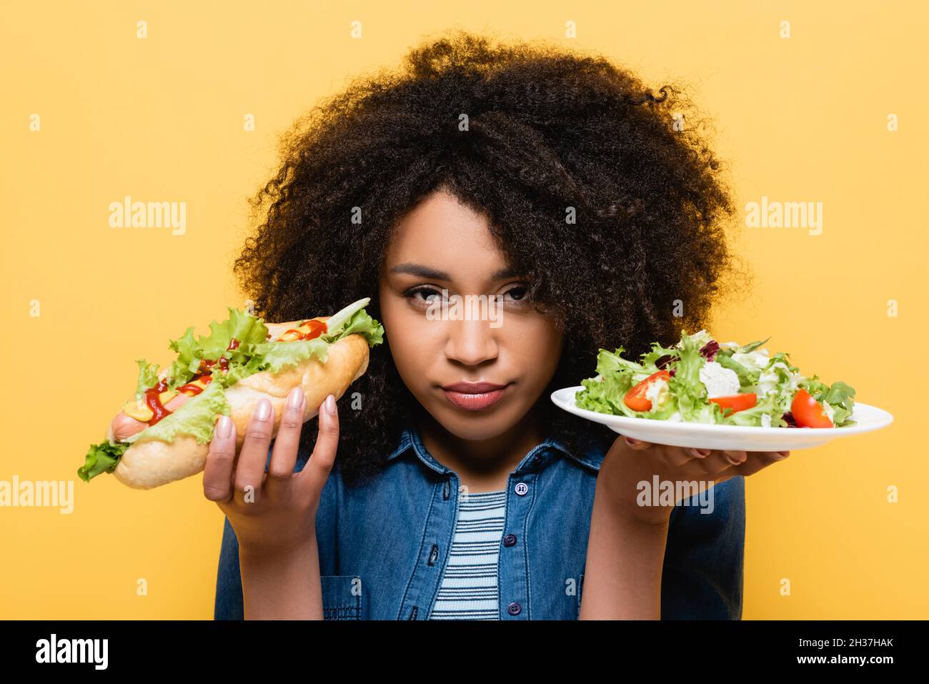 african american woman looking at camera while holding fresh vegetable ...