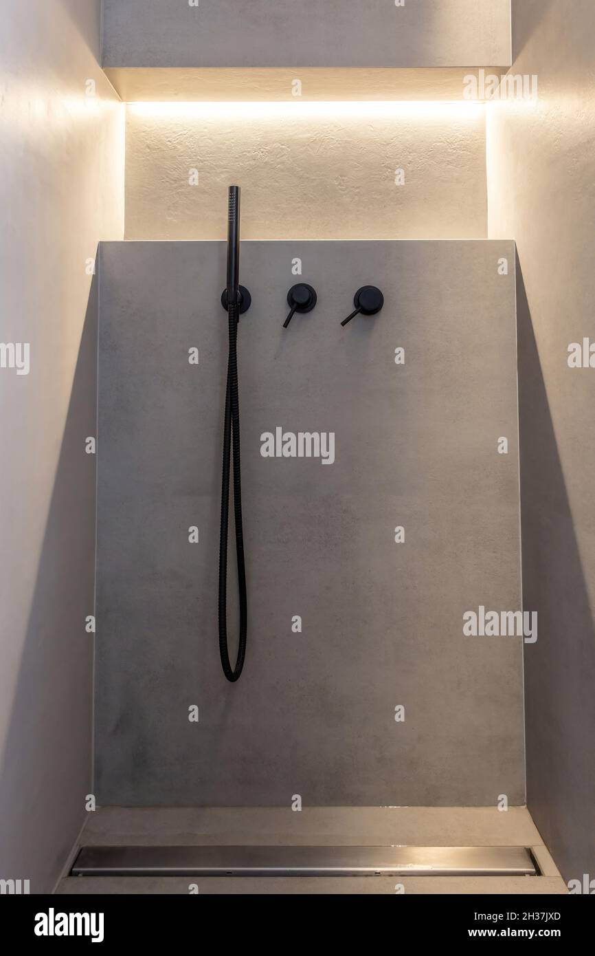Bathroom interior detail with hand shower taps and linear led light ...