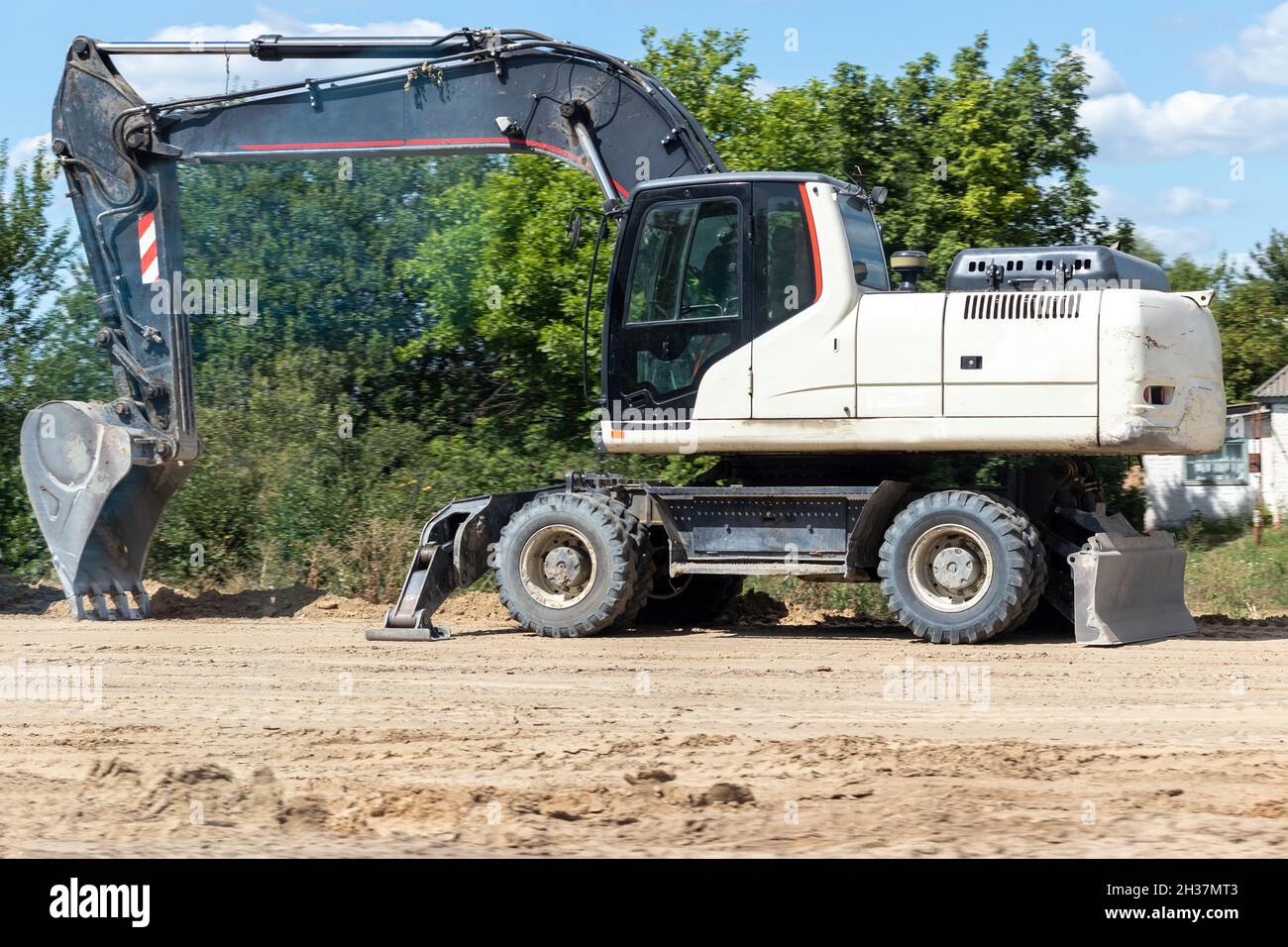 Modern white excavator standing on a ground. Digger with a bucket. Road ...