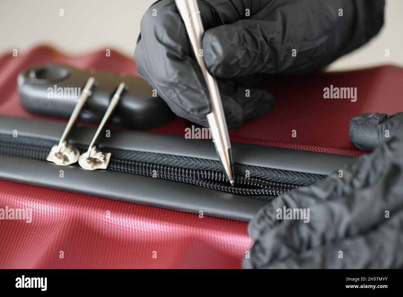 Thief in black gloves opening suitcase lock with ballpoint pen closeup ...