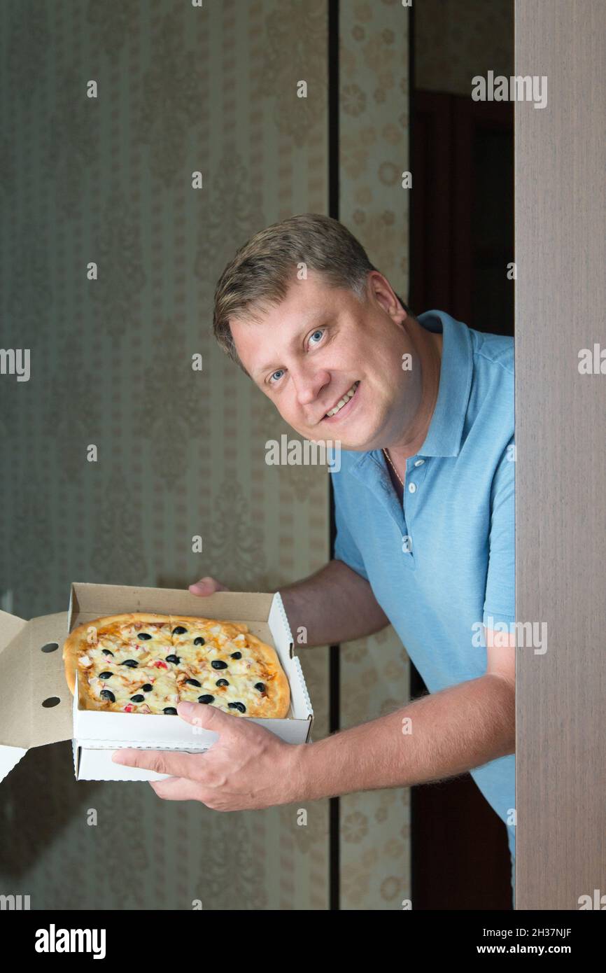 smiling man with a smile looks into room and invites you to eat pizza ...