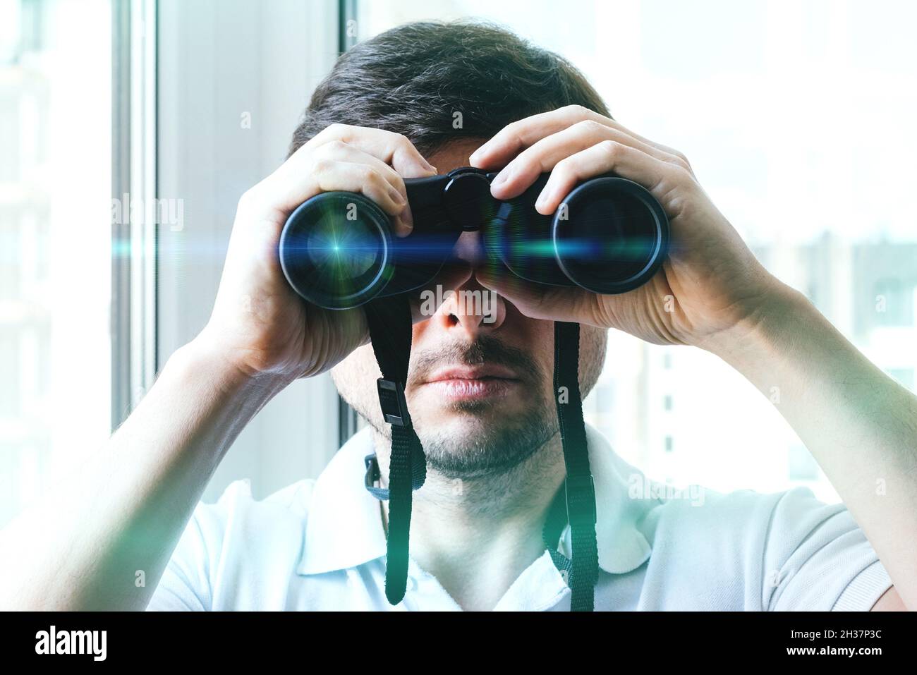 Handsome bearded man looking through binoculars with bright green and ...
