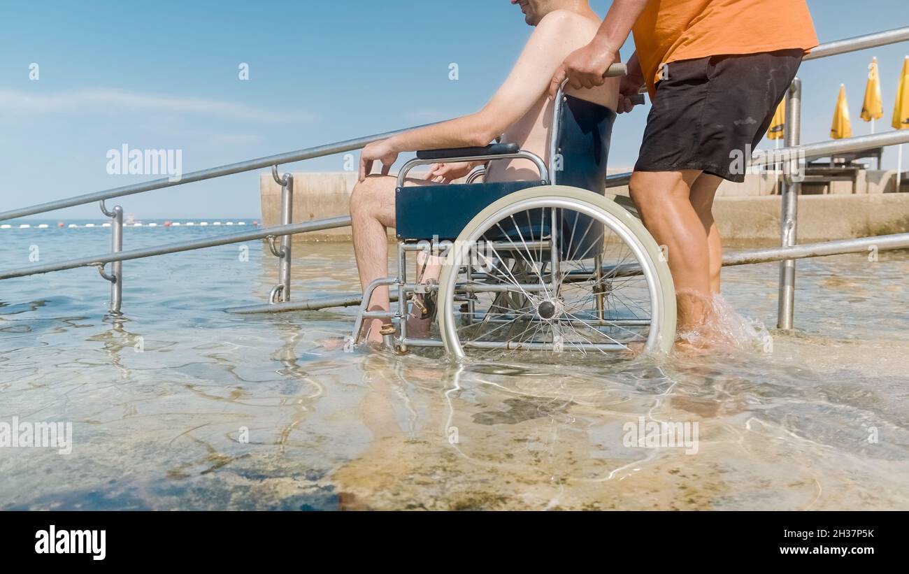 Man with disability on a wheelchair being transported into sea for ...