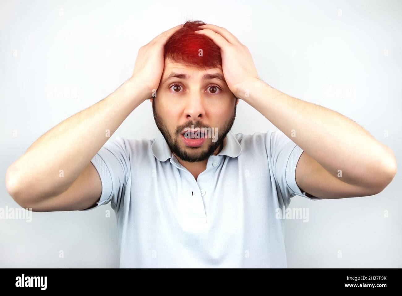 Surprised bearded man with eyes and mouth wide open, holding his head ...