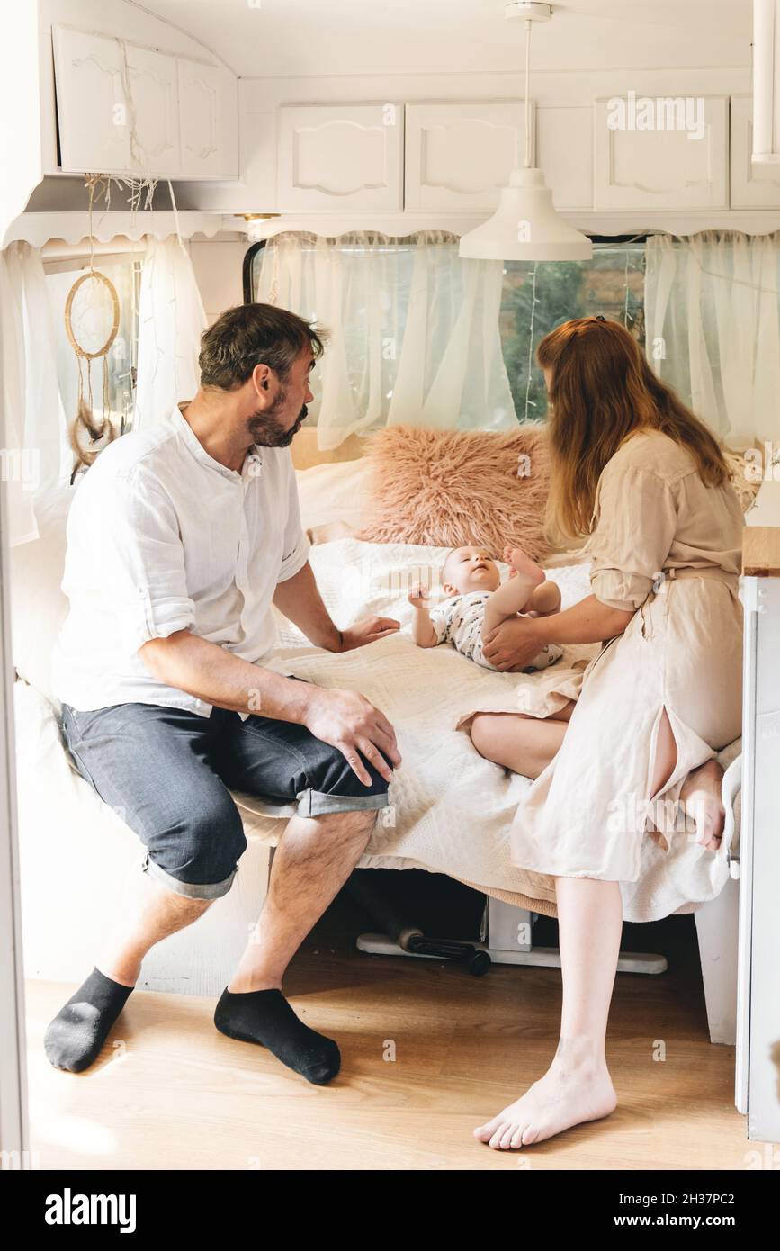 Family with baby on the bed in trailer in the morning. Newborn child ...