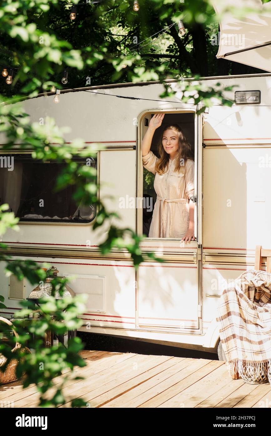 Camping and travelling . Happy person relaxing outdoors near trailer ...