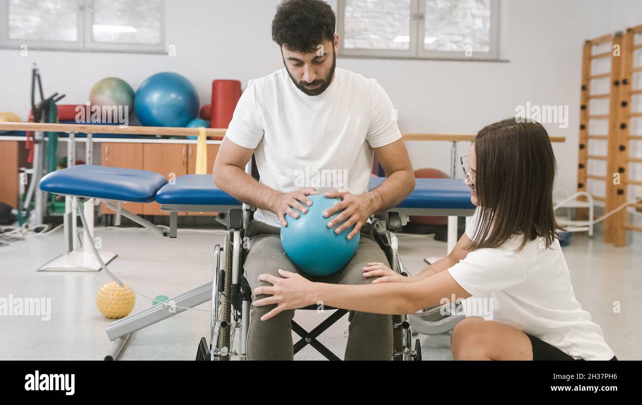 Man with disability in a wheelchair, doing an exercise with a smaller ...