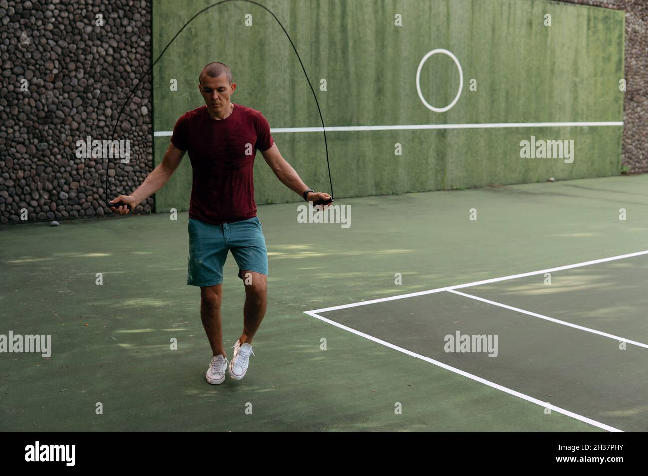 man jumping rope on the tennis court. bali Stock Photo - Alamy