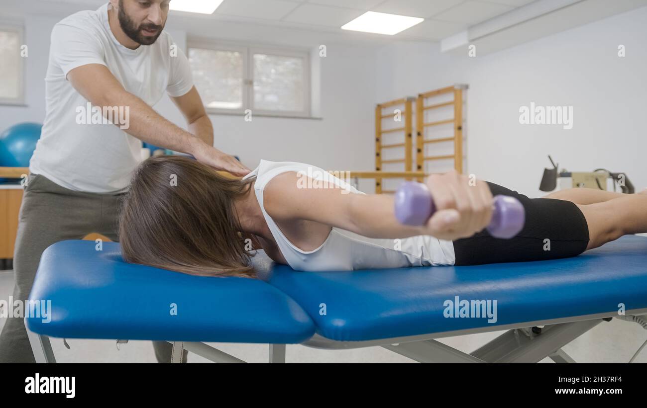 Woman doing shoulder stabilization exercises with small weights, with a ...