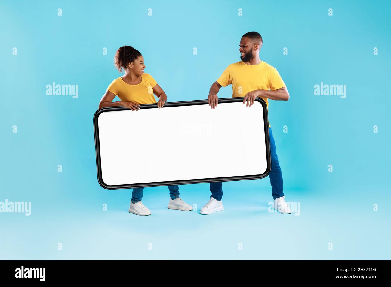 Angry young black couple fighting over big smartphone with blank white ...