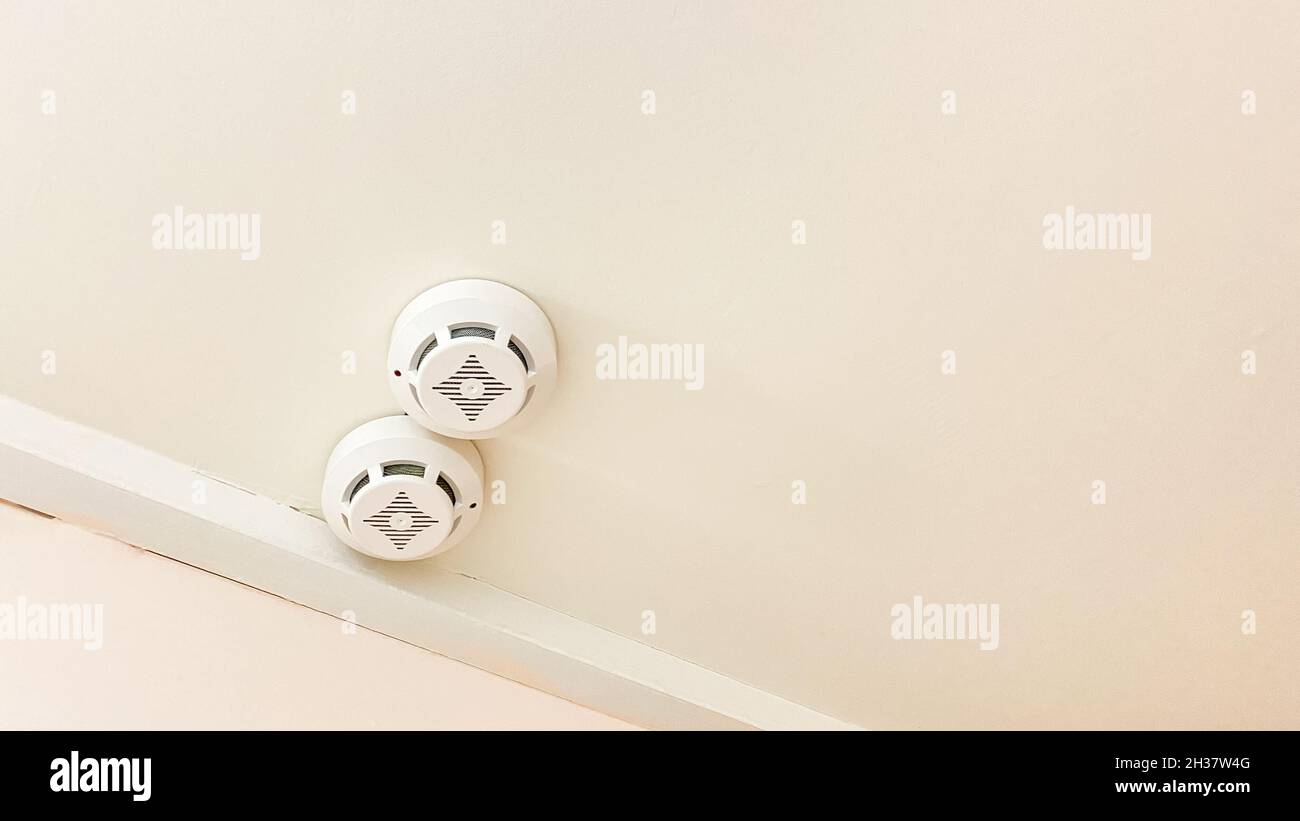Two smoke detectors are installed on the ceiling in a residential ...