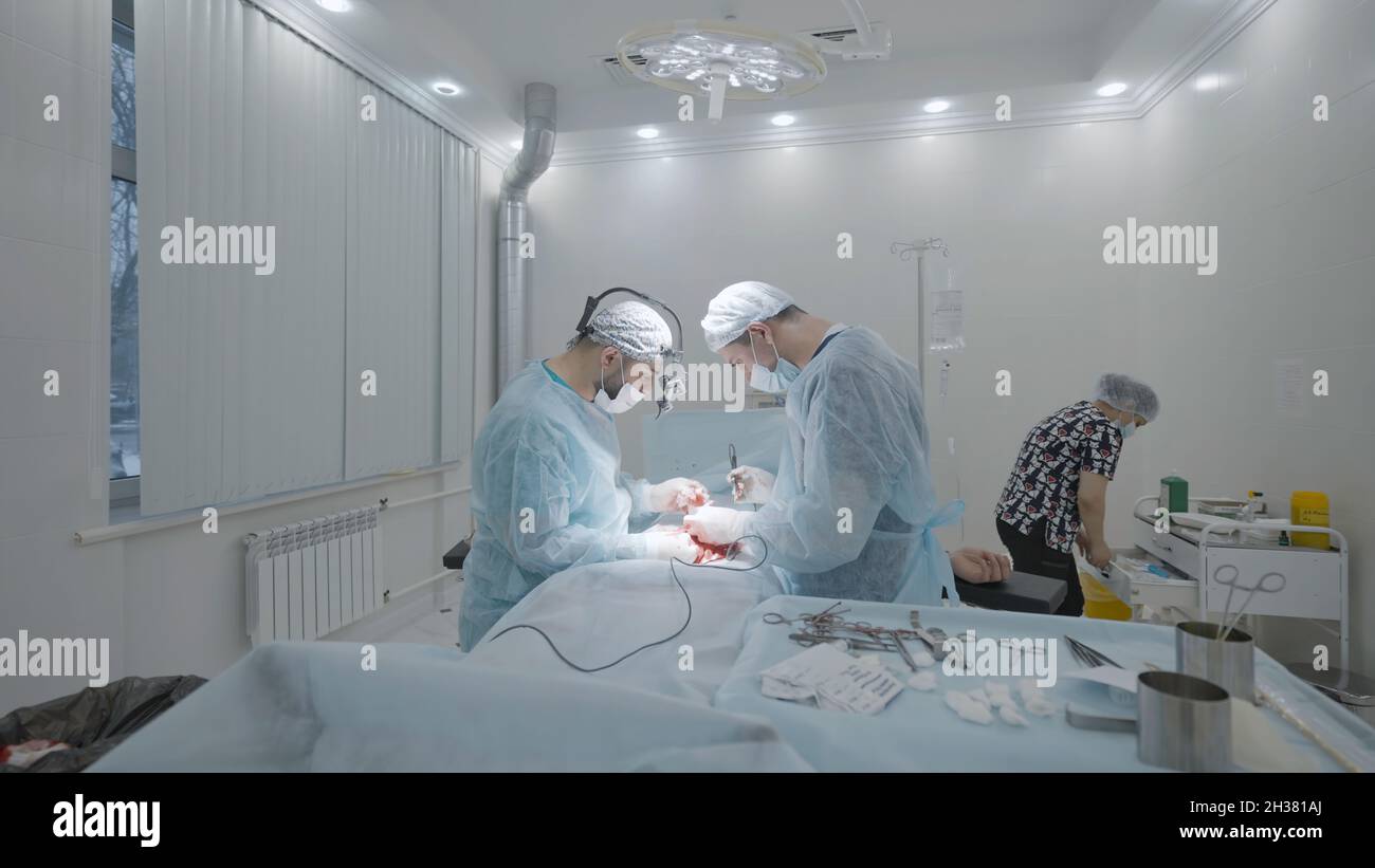 Operating room during operation with two surgeons. Action. Side view of ...