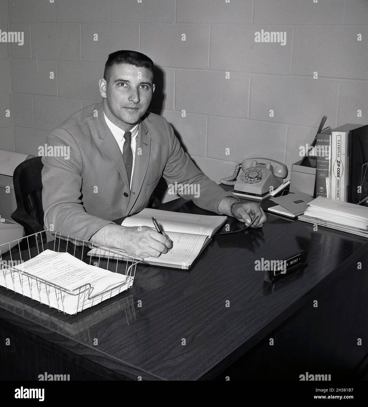 1968, historical, a young male adminstrator sitting at his desk, with ...