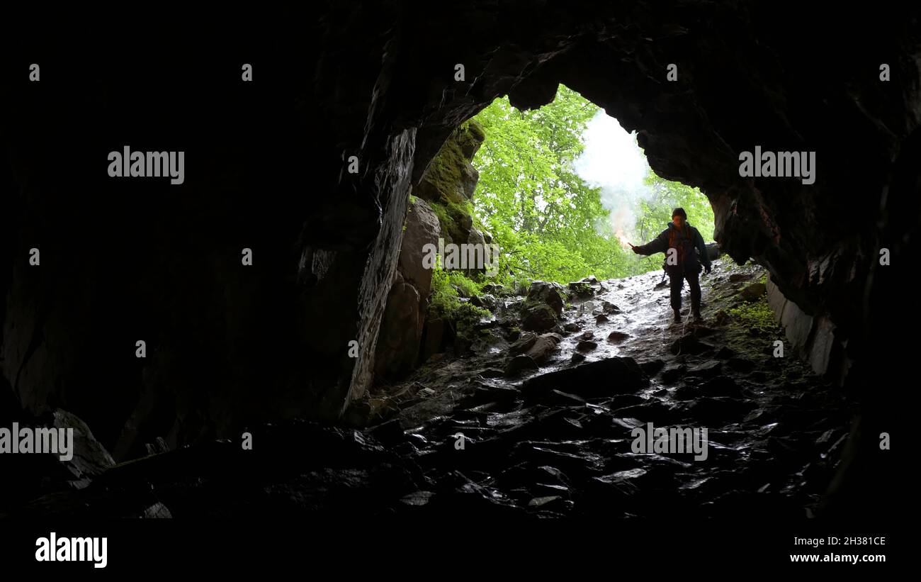 Hiker down into cave. Stock footage. Traveler with red signal candle ...