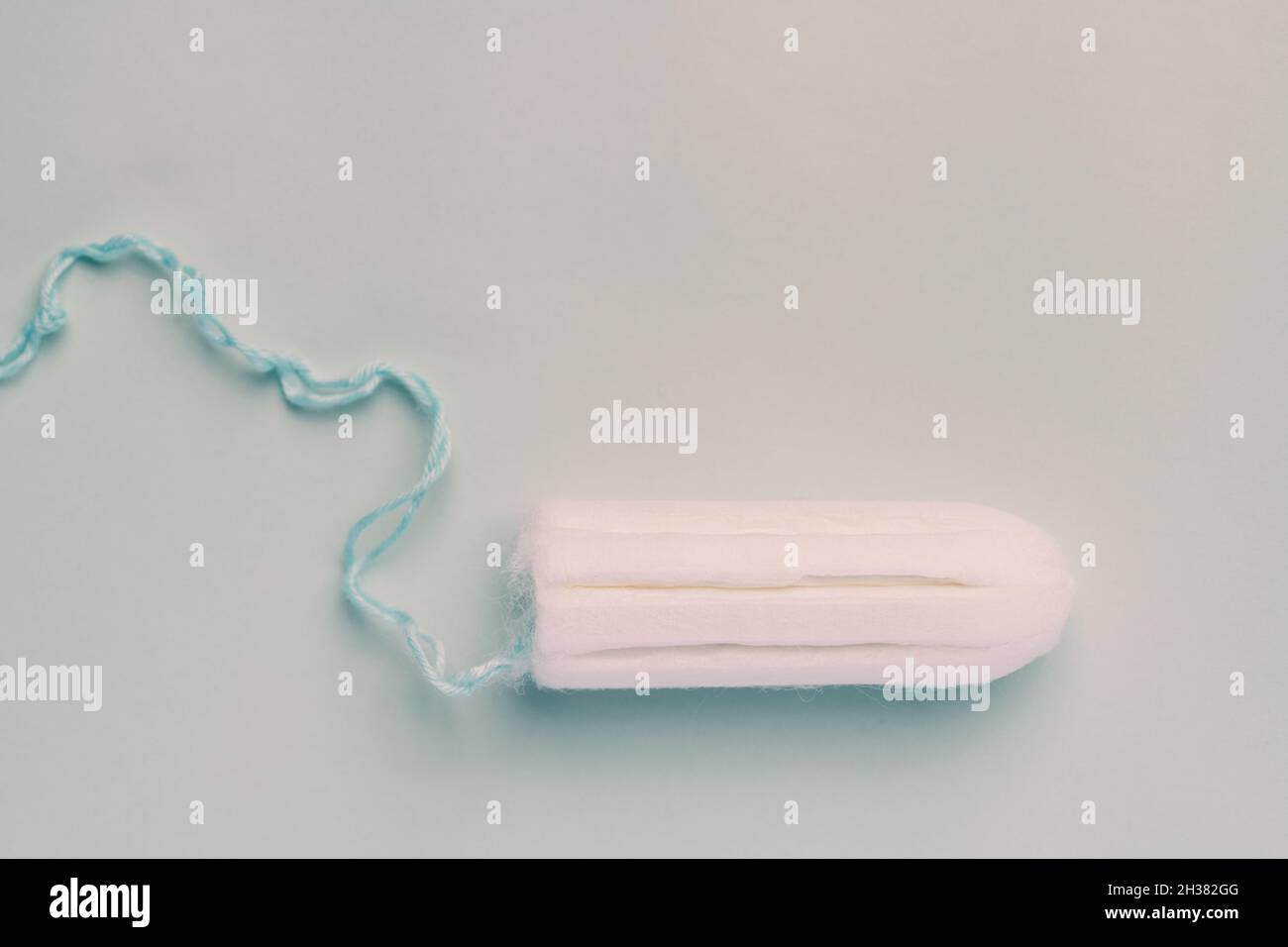 Clean cotton tampon on pastel blue background. Female intimate hygiene ...
