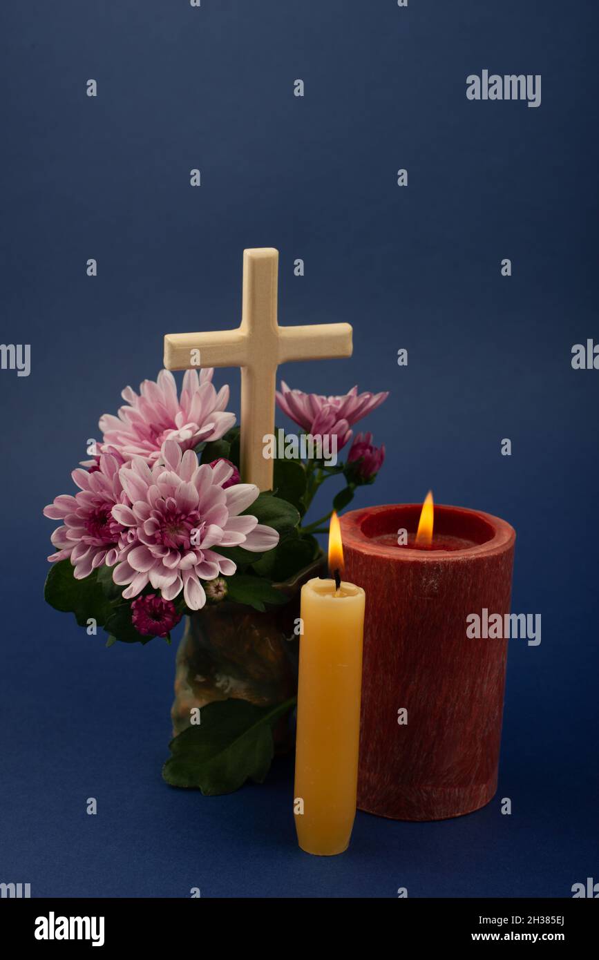 Composition of burning candle, flowers and wooden cross for all souls ...