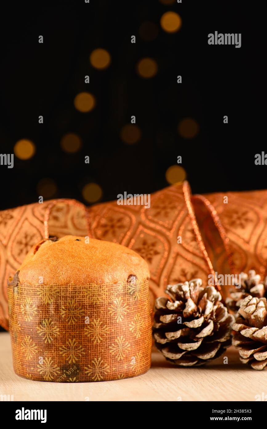 small panettone next to pine cones and decorative ribbon with dark ...