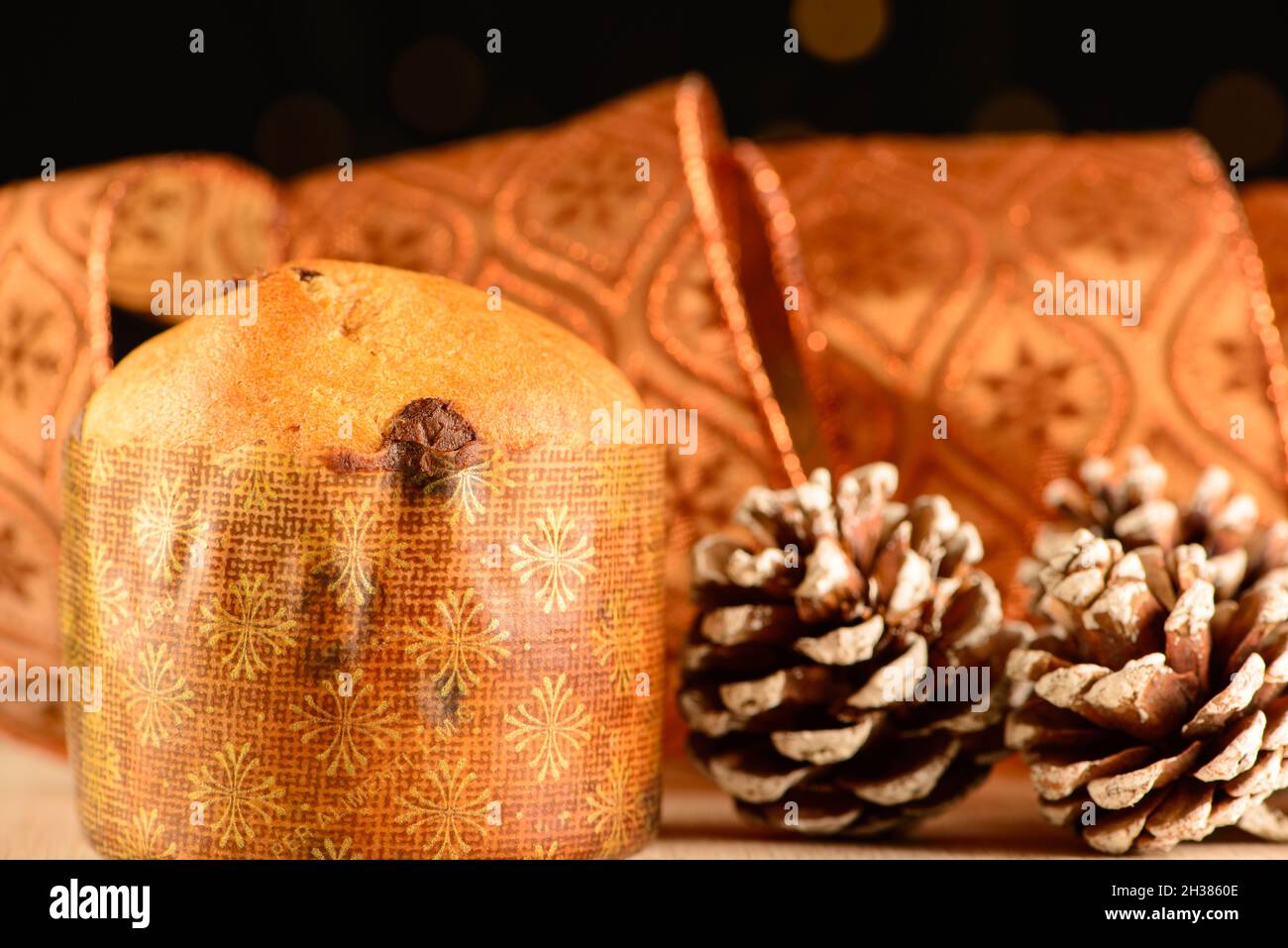 small panettone next to pine cones and decorative ribbon with dark ...