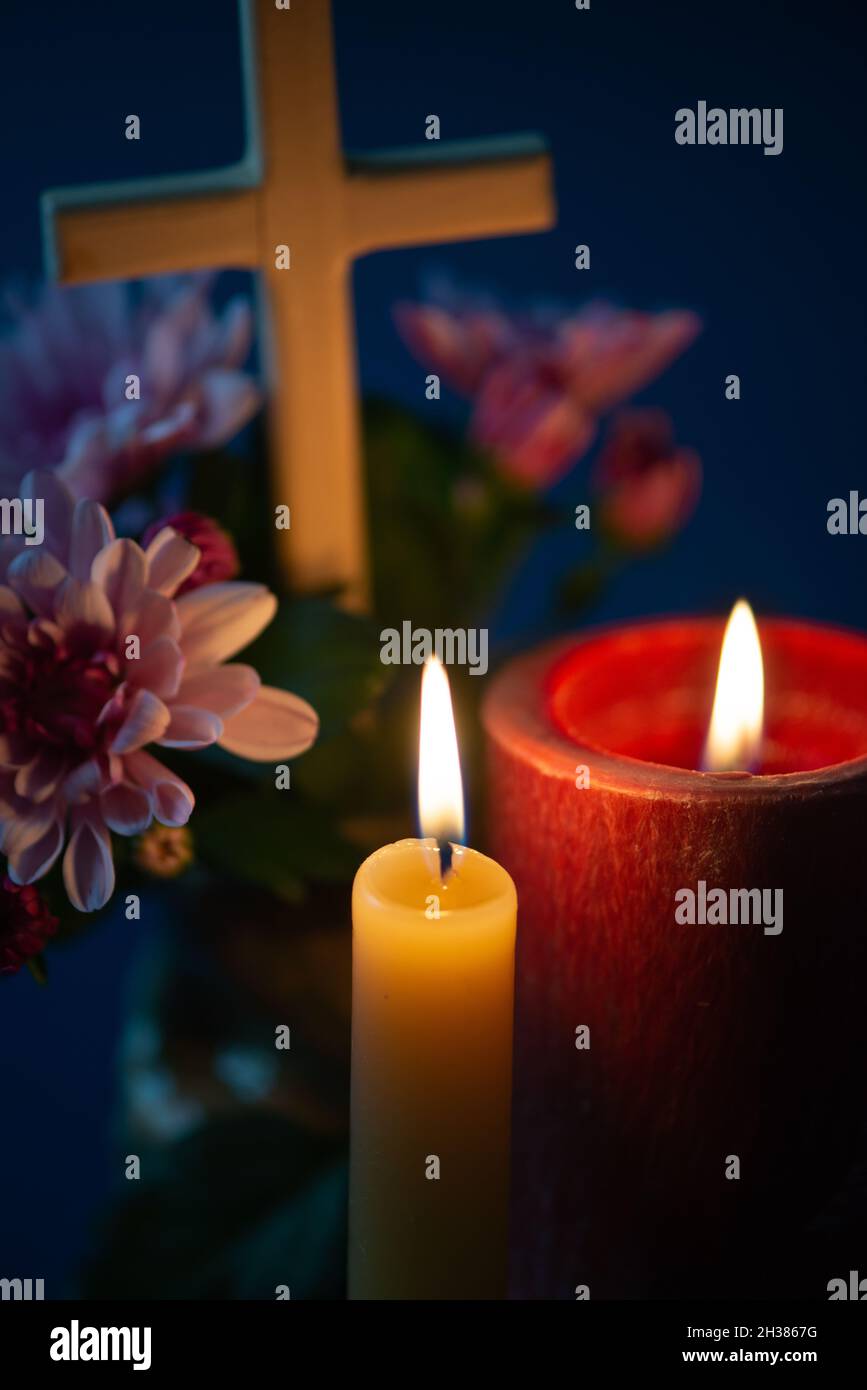 Composition of burning candle, flowers and wooden cross for all souls ...