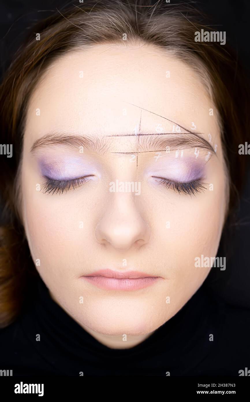 a model girl with her eyes closed lies on the eyebrow marking procedure ...