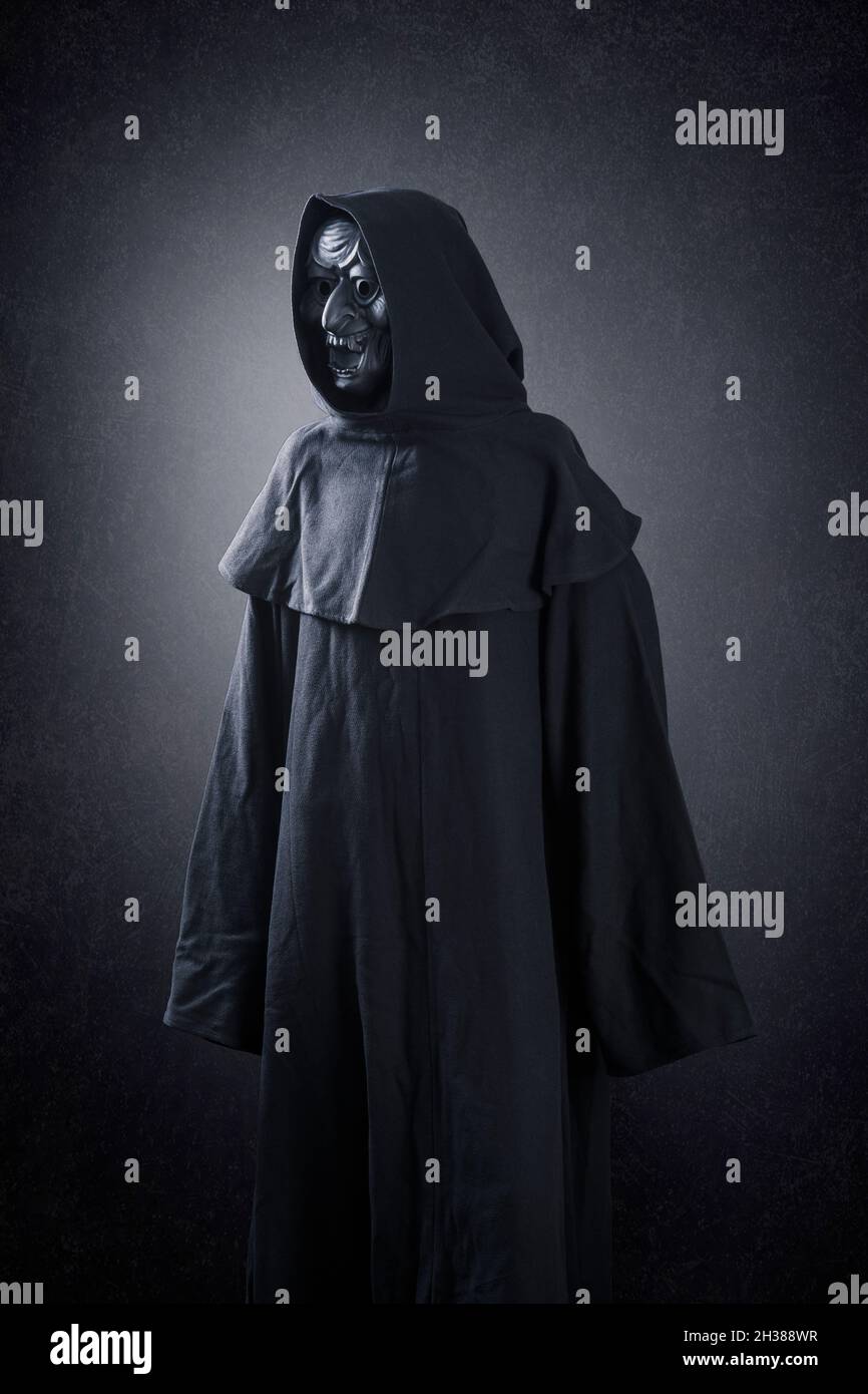Spooky figure with hooded cape over dark misty background Stock Photo ...