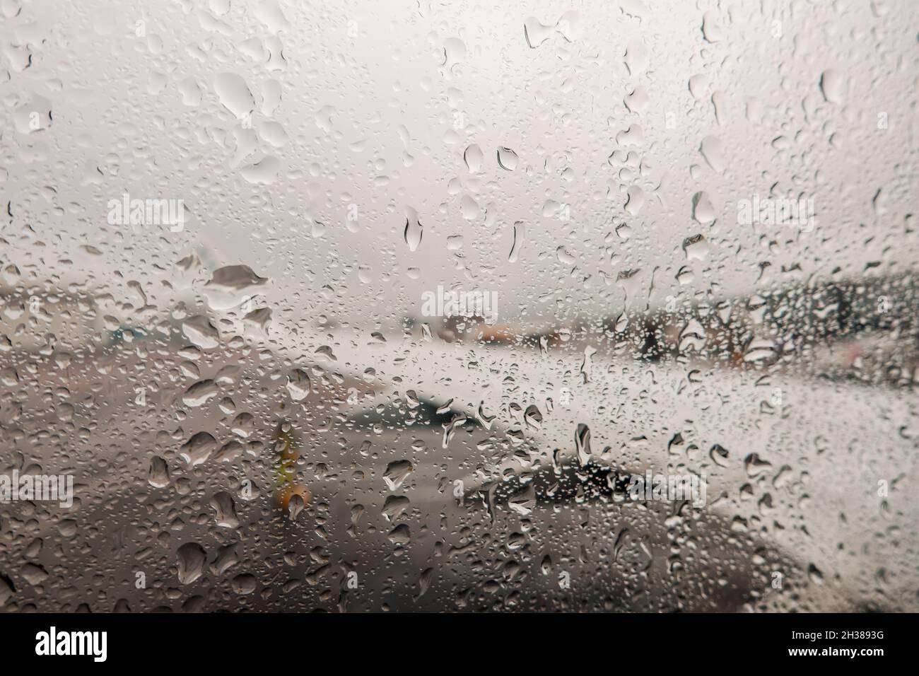 View of airplane wing through passenger window with rain drops at rainy ...